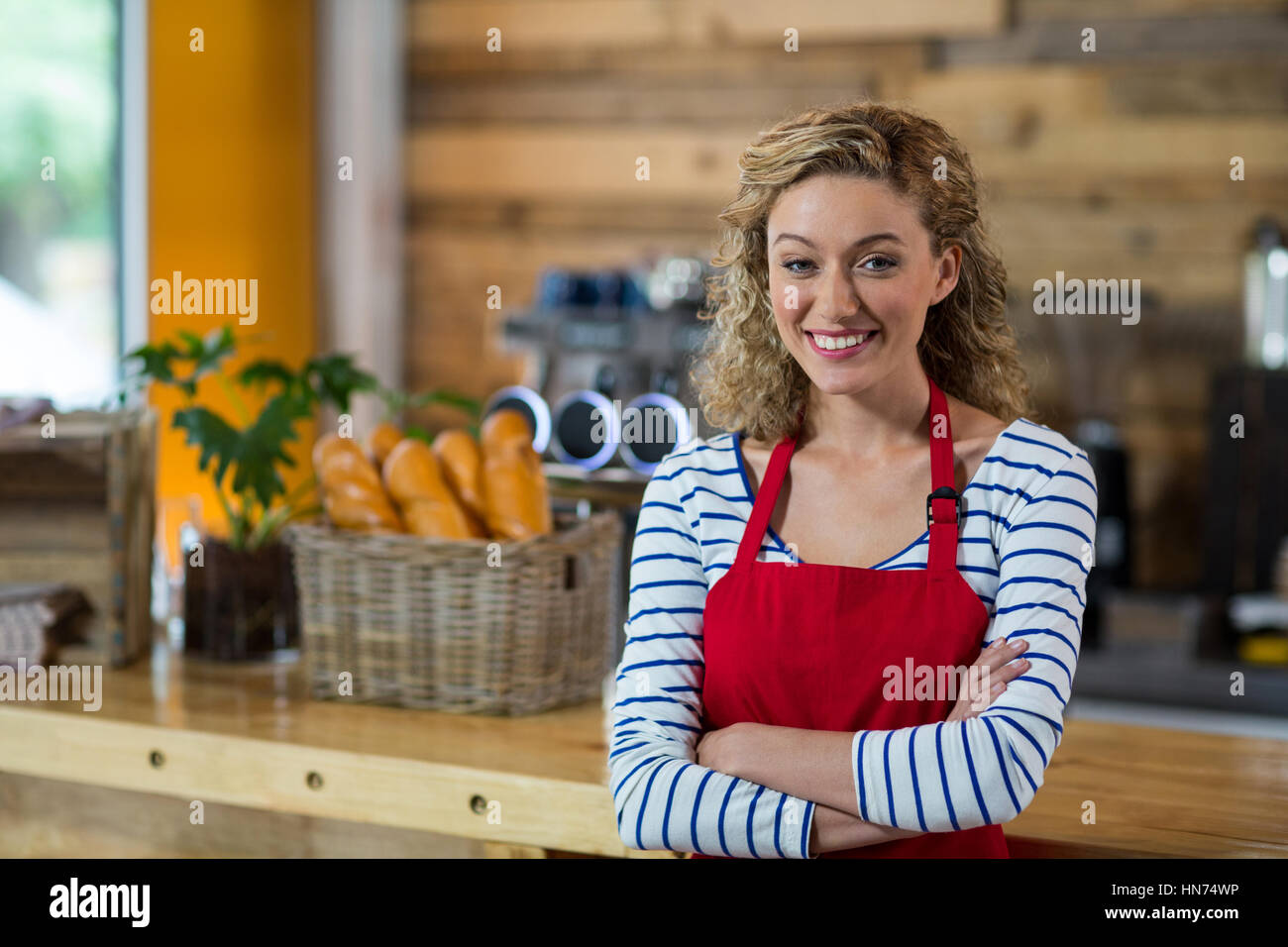 Portrait of smiling waitress standing with arms crossed in cafe Stock ...