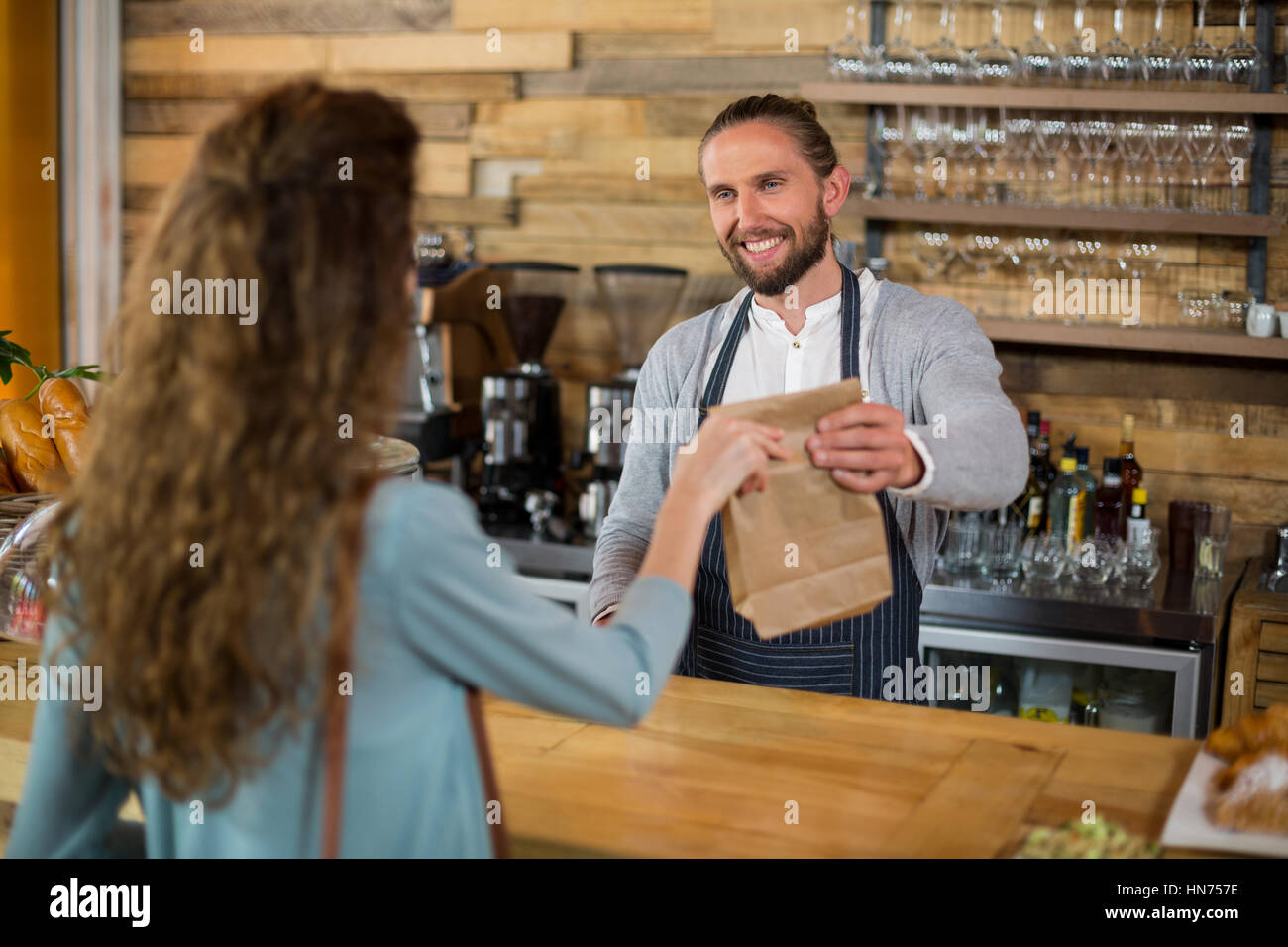 Woman receiving parcel from waiter at counter in cafe Stock Photo - Alamy