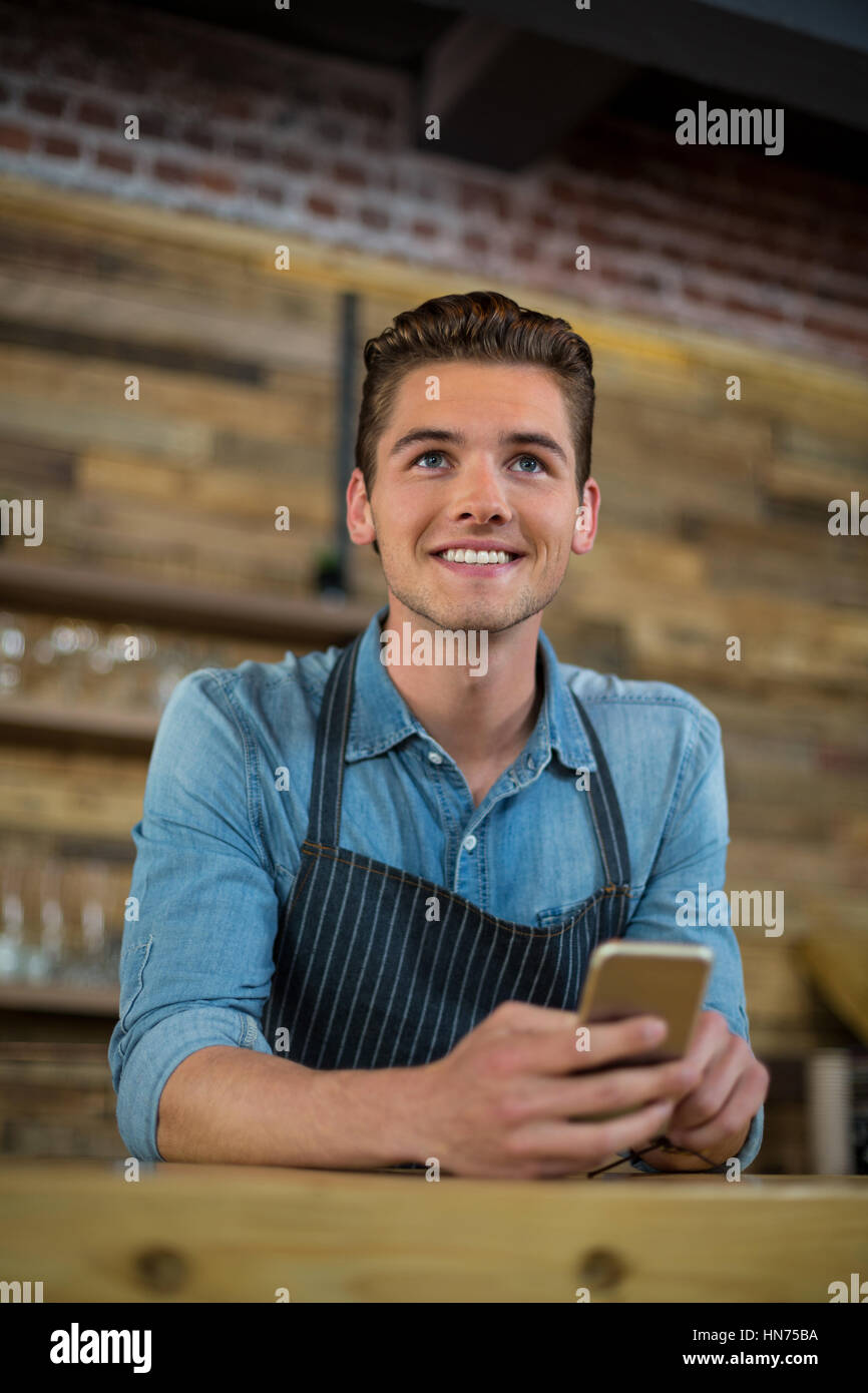 Smiling waiter using mobile phone at counter in cafÃƒÂ© Stock Photo - Alamy
