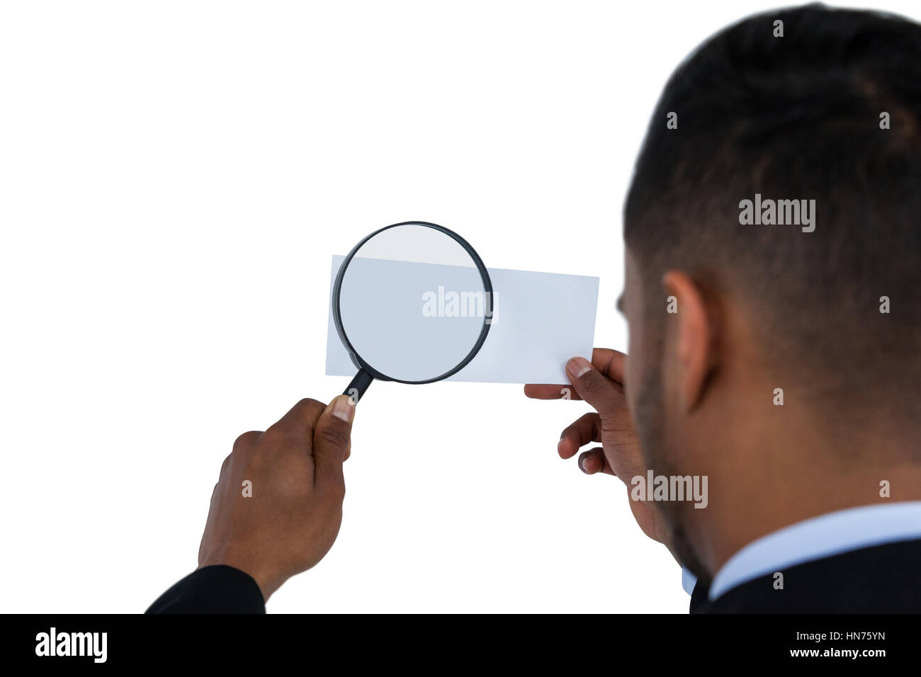 Rear view of man holding magnifying glass on paper against white ...
