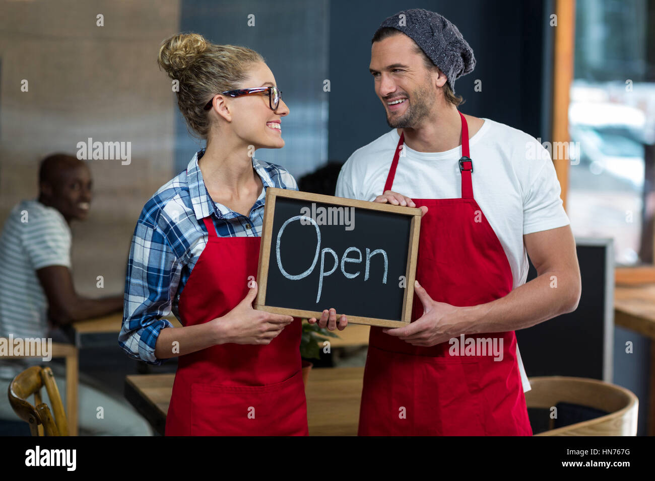 Smiling waitress and waiter standing with open sign board in cafÃƒÂ ...