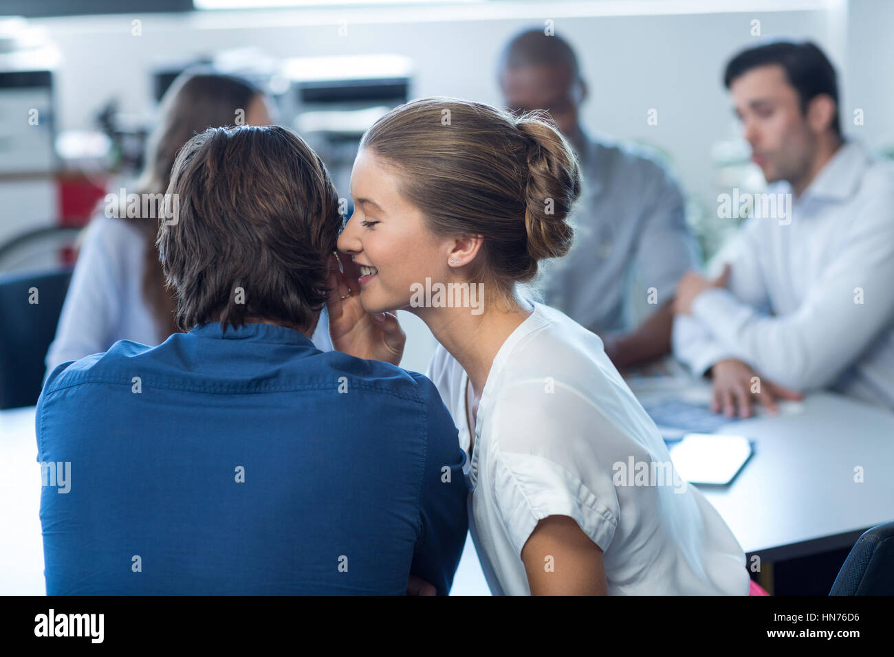 Female business executive whispering to her colleague in office Stock ...