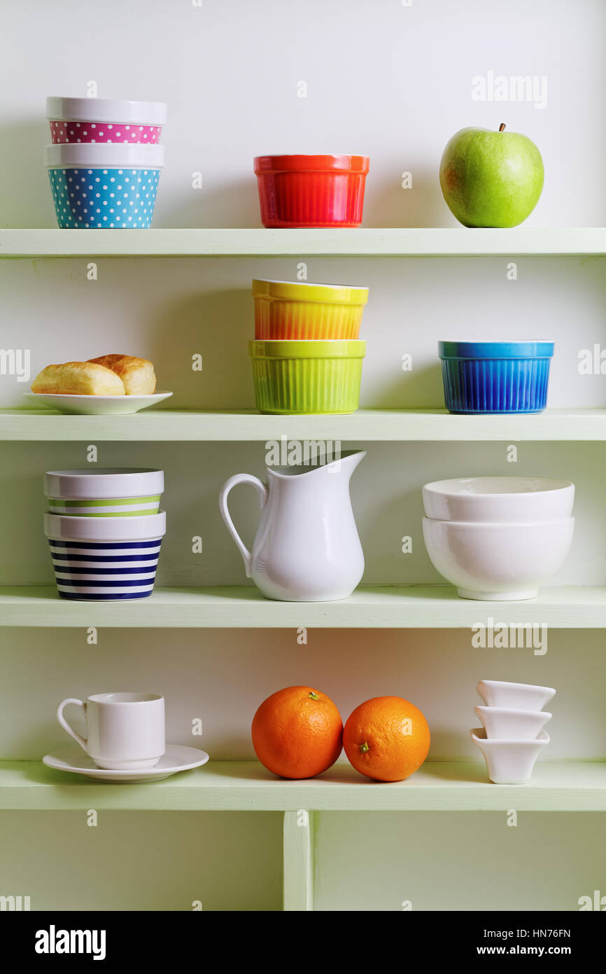 Variety of ceramics on shelf. Colorful bowls, cups and white dishware ...