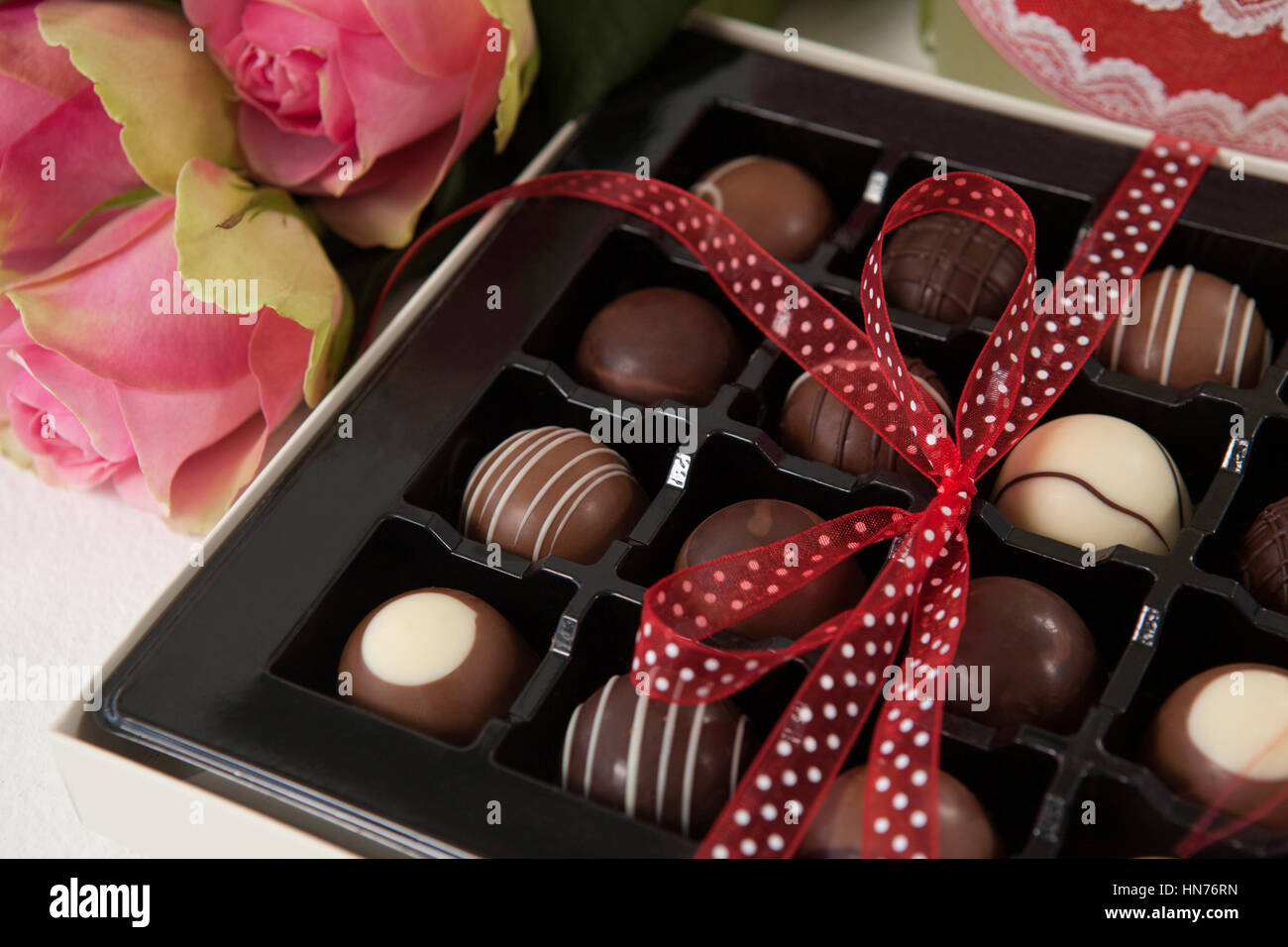 Bunch of roses and assorted chocolate box against white background ...