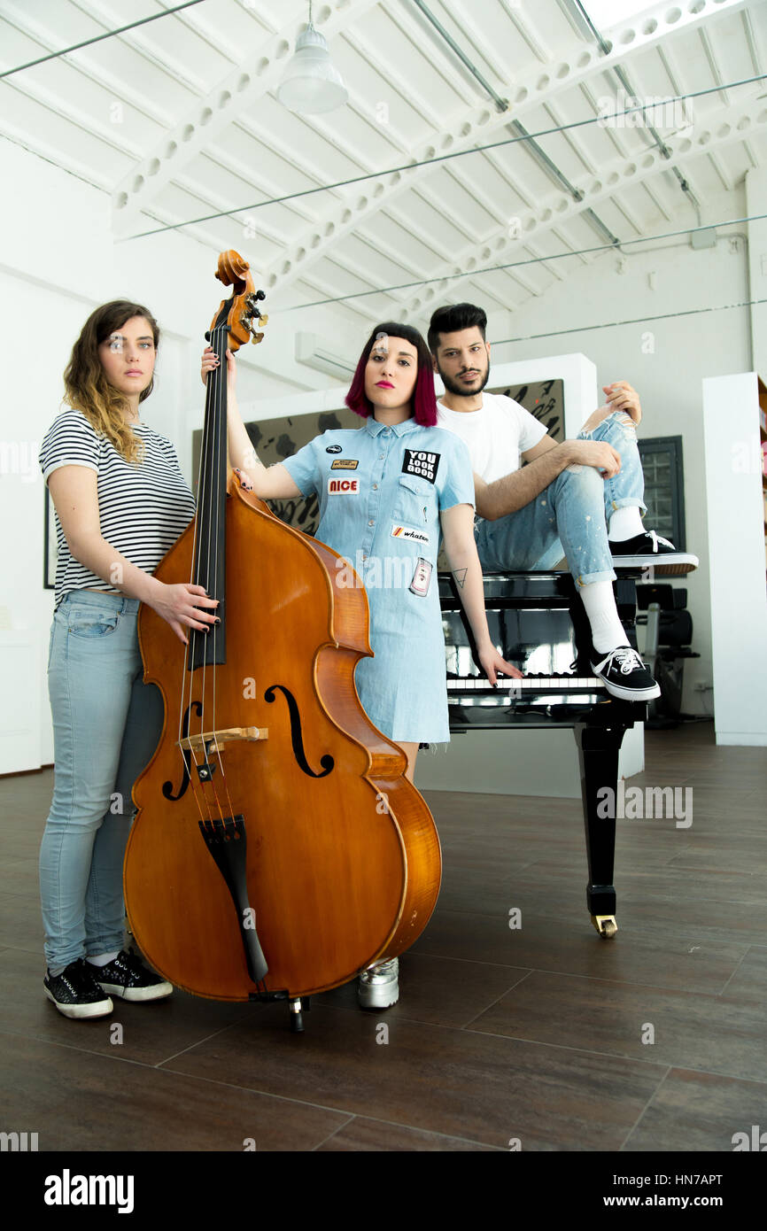 Group of musicians standing in front of grand piano holding instruments ...