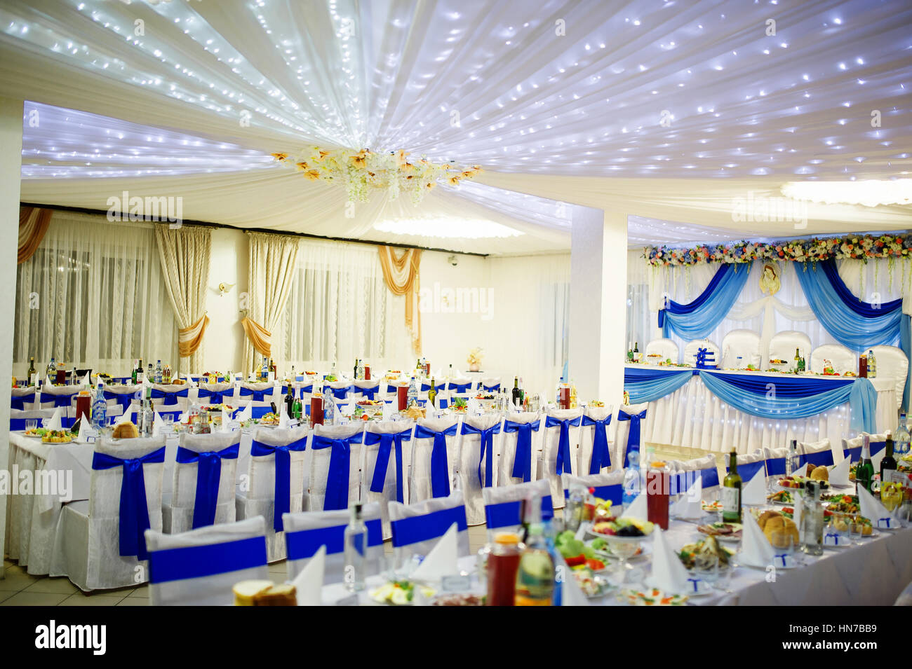 Wedding hall with chairs and table with blue ribbons Stock Photo - Alamy