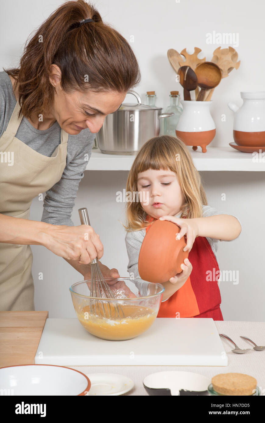three years old child and woman, in teamwork, making and cooking a ...