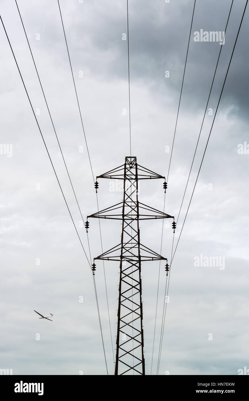 Power cable tower and a small plane on overcast day Stock Photo - Alamy
