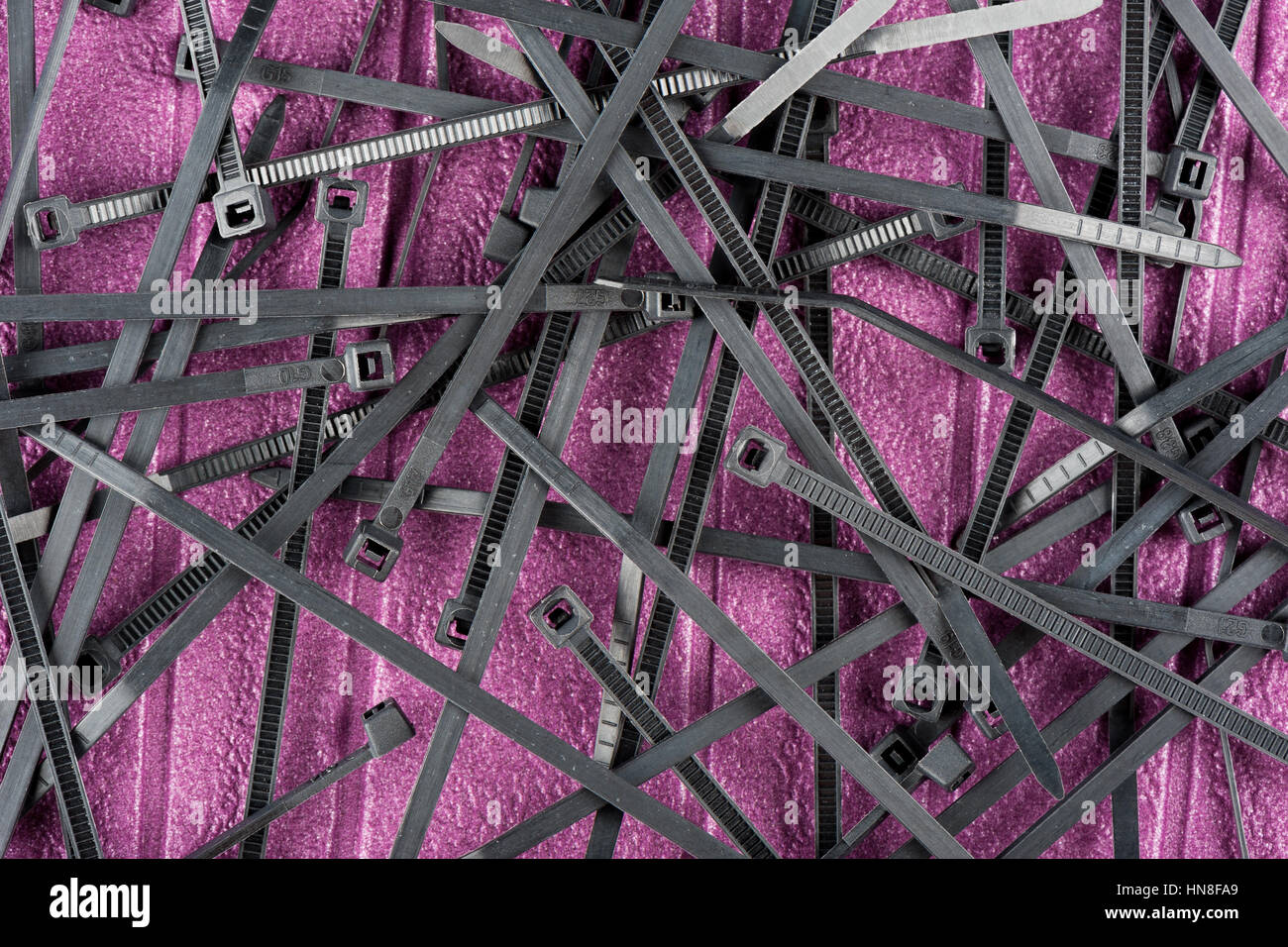 heap of black cable ties on purple background Stock Photo - Alamy