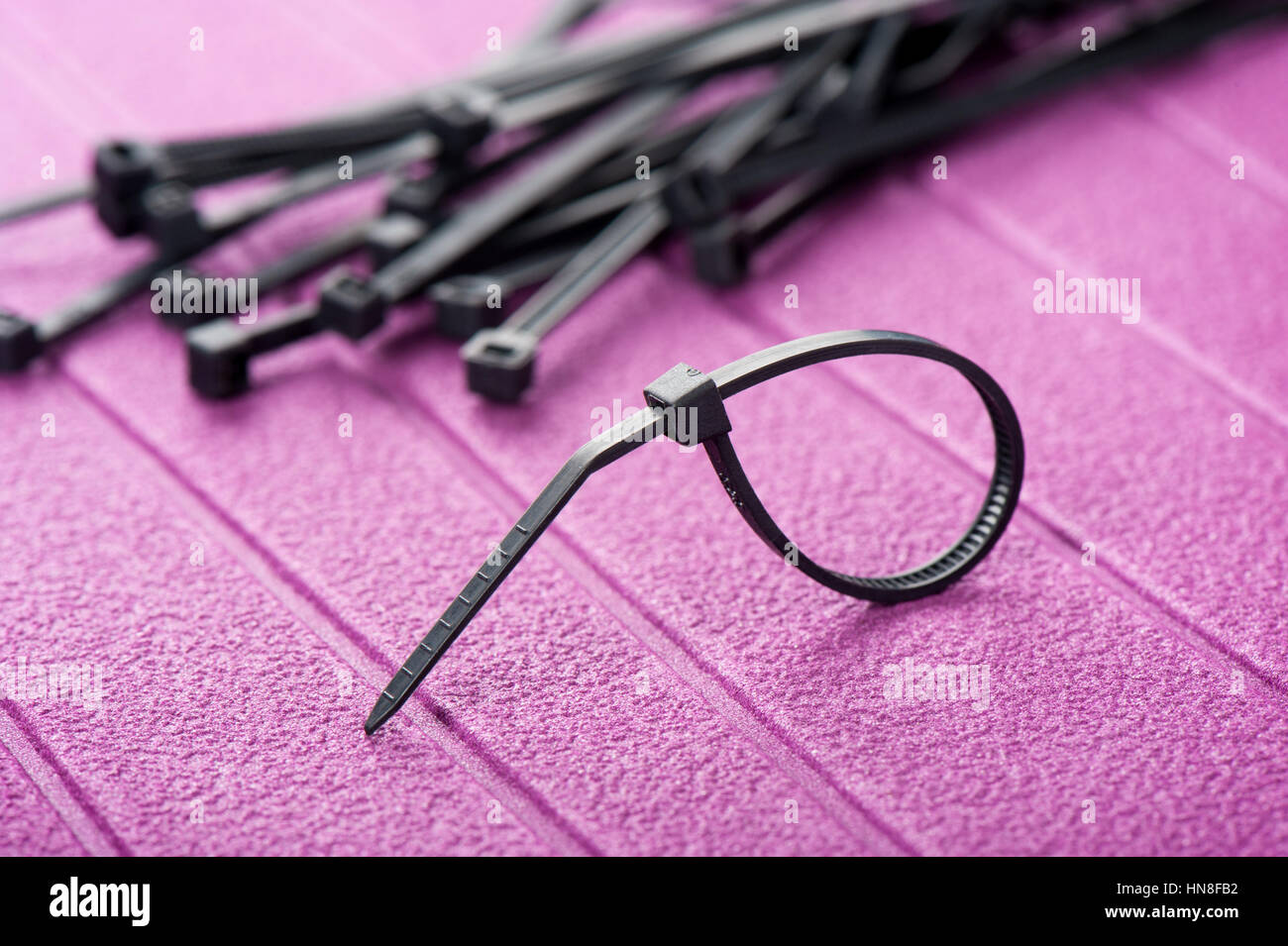 heap of black cable ties on purple background Stock Photo - Alamy