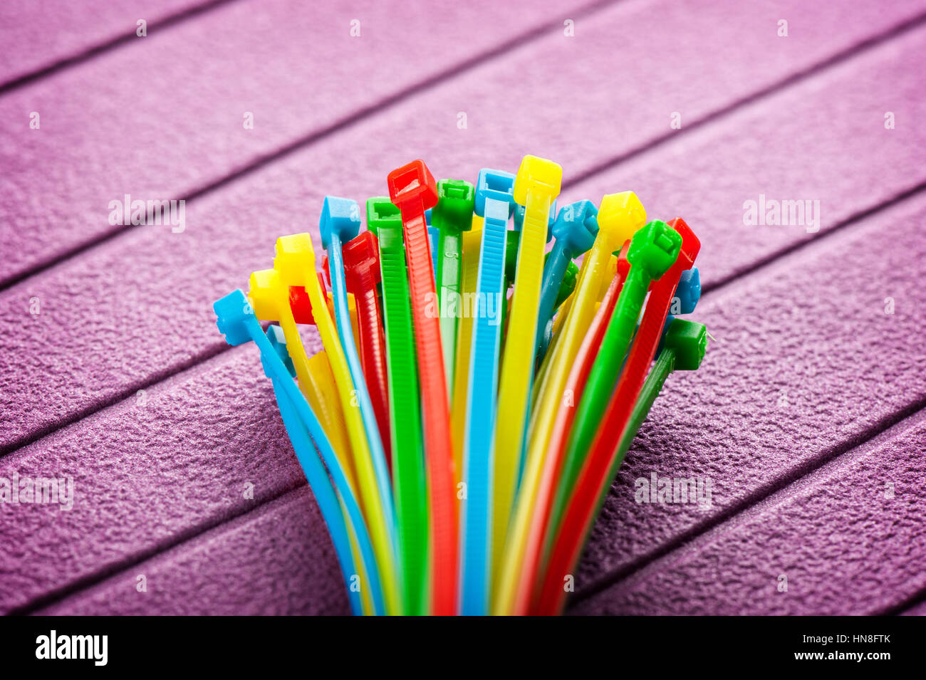 heap of colorful cable ties on purple background Stock Photo - Alamy