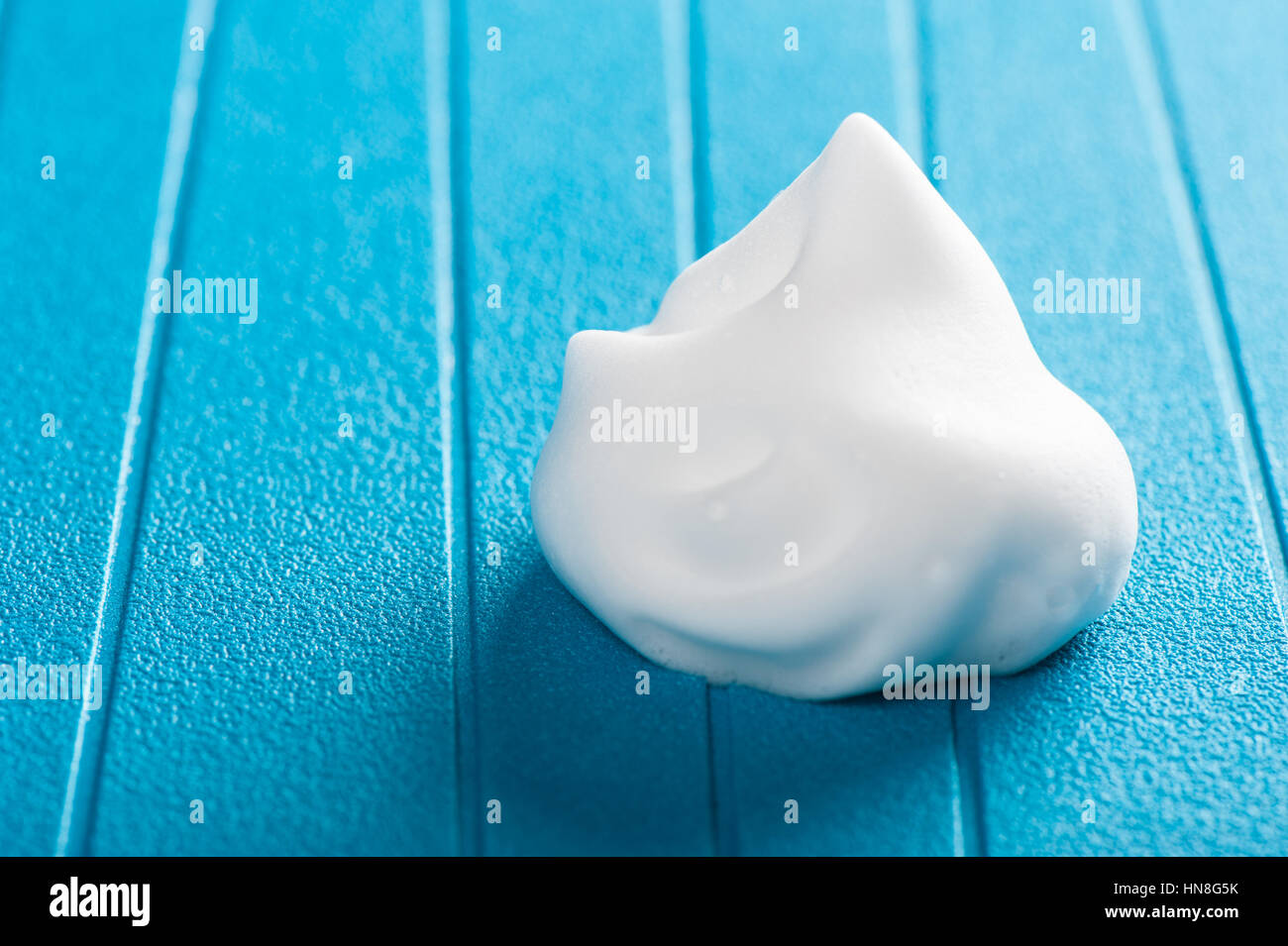closeup white hair mousse on blue background Stock Photo - Alamy
