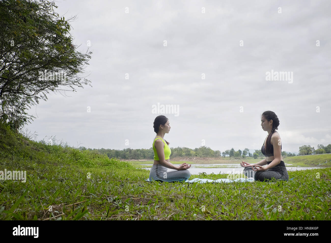 Two young girl doing yoga fitness exercise outdoor in beautiful ...