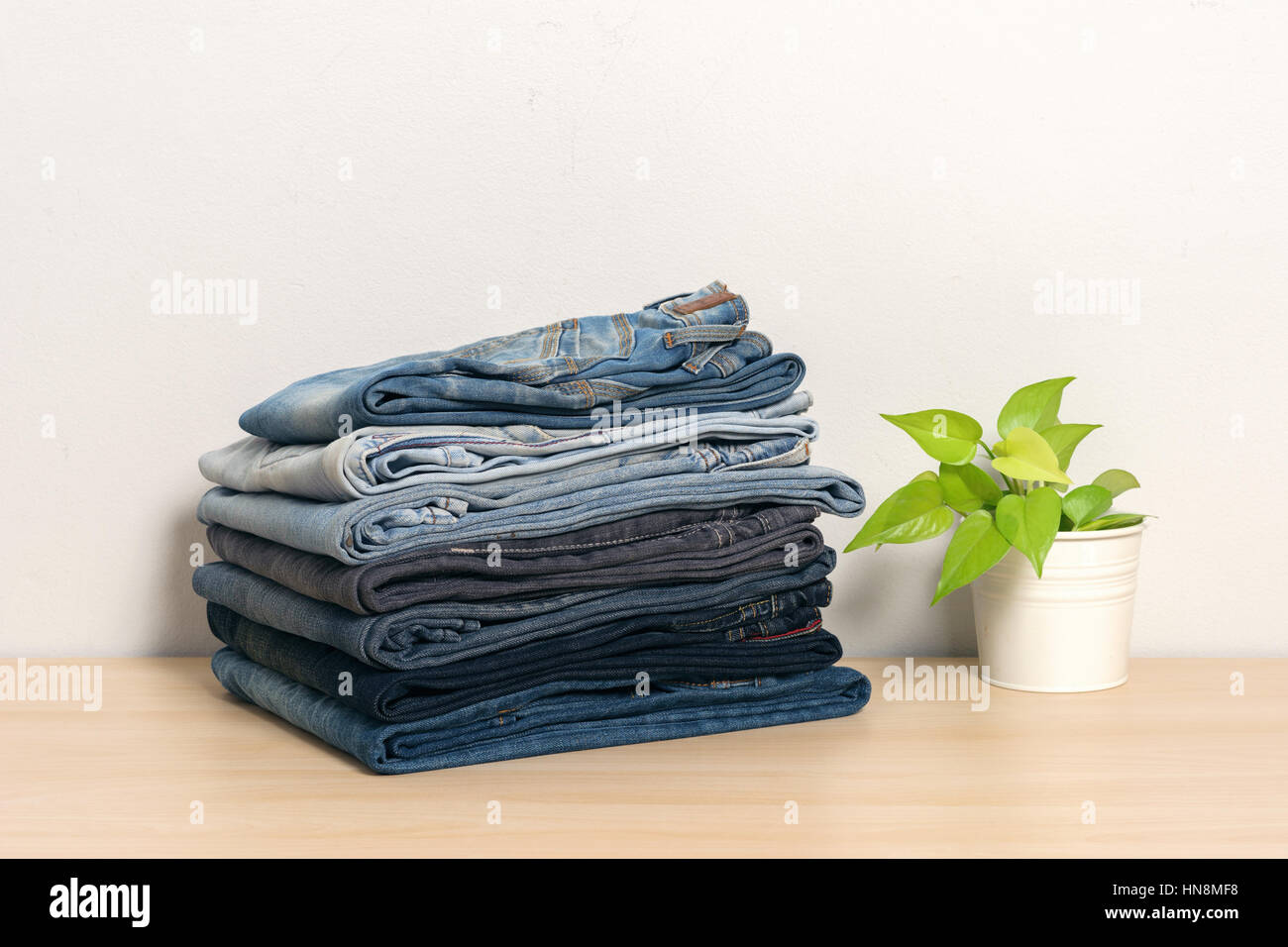 stack of denim jeans isolate on wooden desk Stock Photo - Alamy