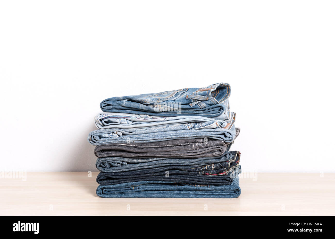stack of denim jeans isolate on wooden desk Stock Photo - Alamy