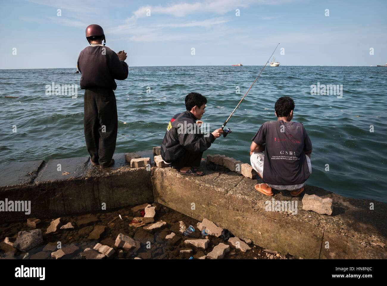 A group of men fishing on sea water in Jakarta coast Stock Photo - Alamy