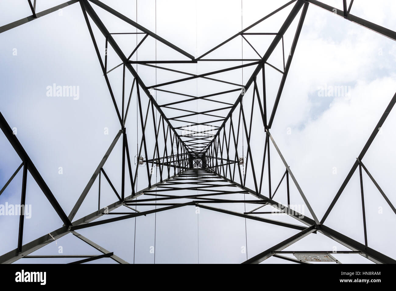 High voltage pylon against cloudy sky. Bottom view. Pattern of metal ...