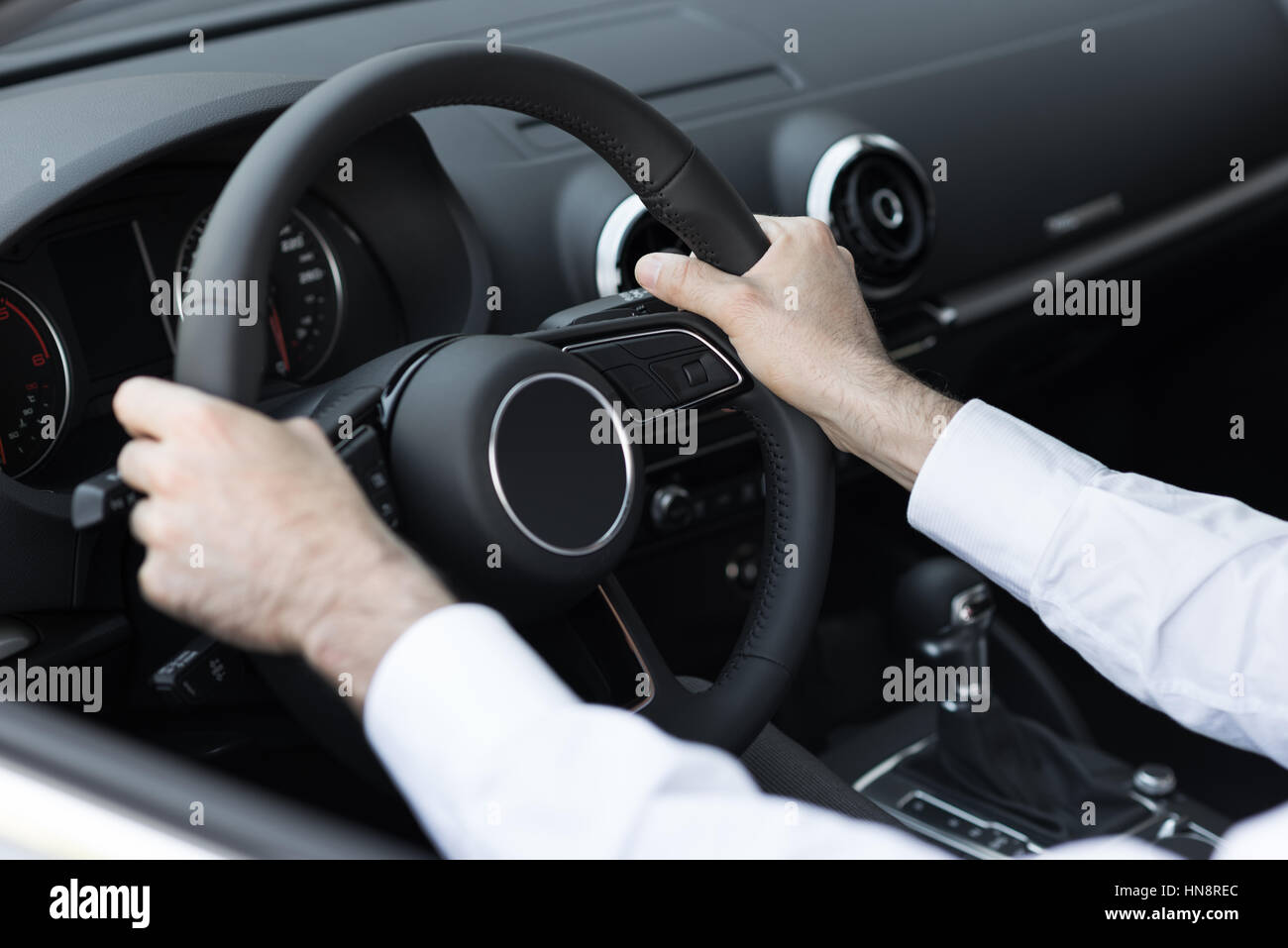 Successful businessman driving his car, hands on steering wheel close ...
