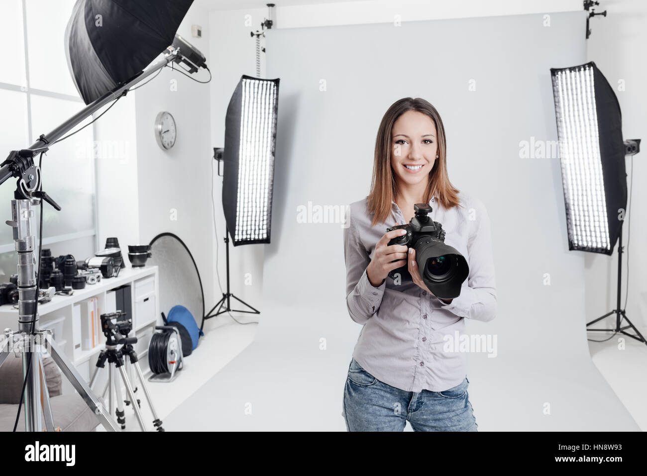 Young female photographer posing in the photo studio, she is smiling ...