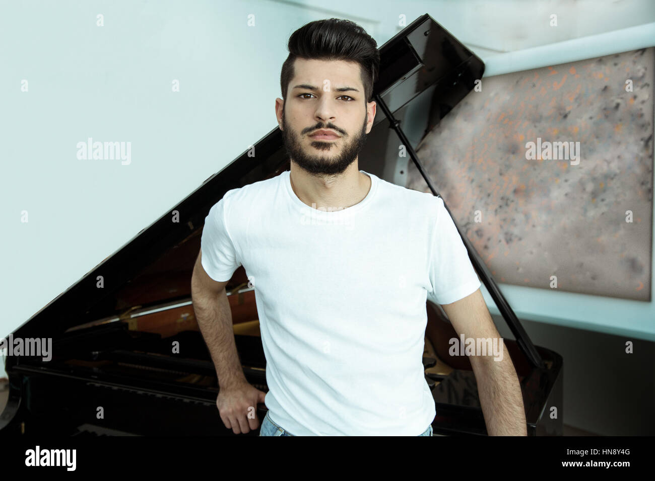 Portrait of a Young caucasian male musician in front of Grand piano ...