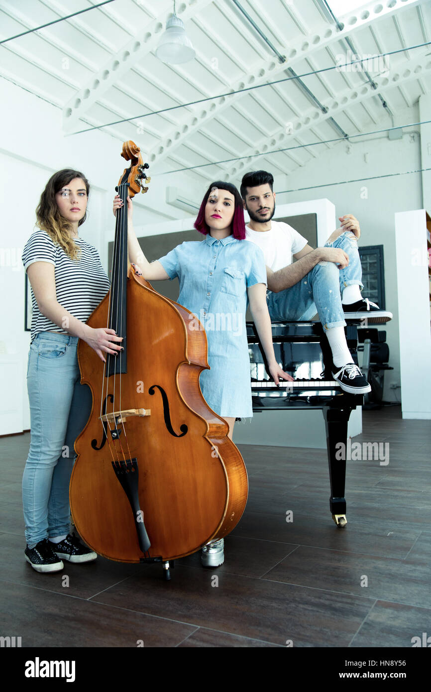 Group of musicians standing in front of grand piano holding instruments ...