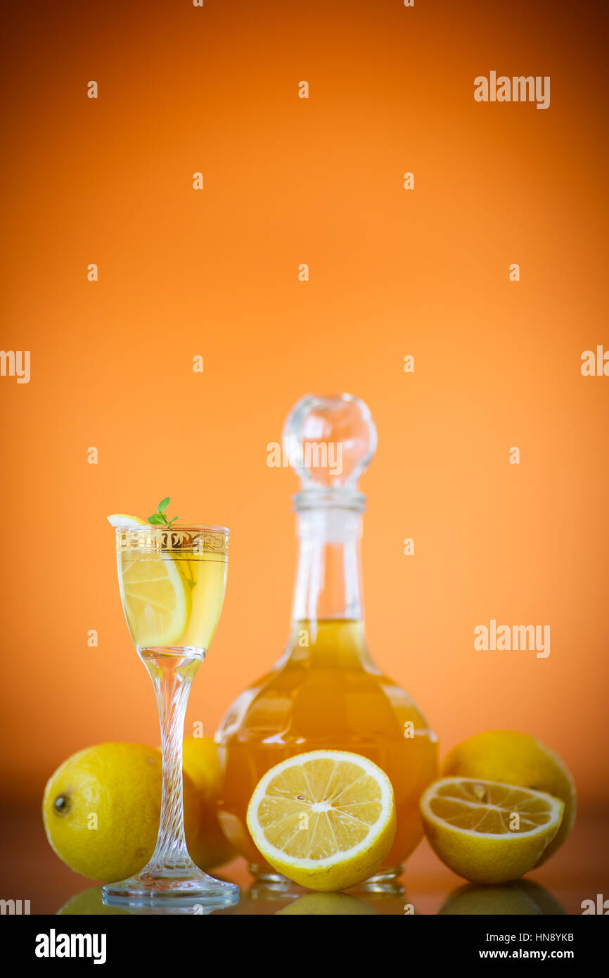 sweet lemon alcoholic brandy in the decanter on an orange background ...