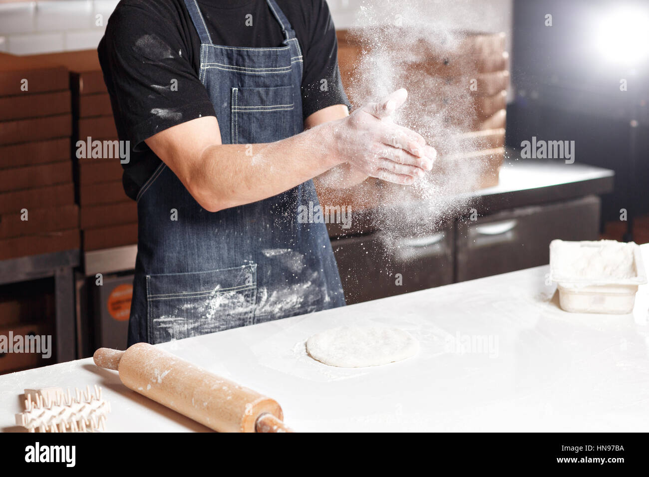 Roll out the dough. expanding cloud of flour. Closeup hand of chef ...