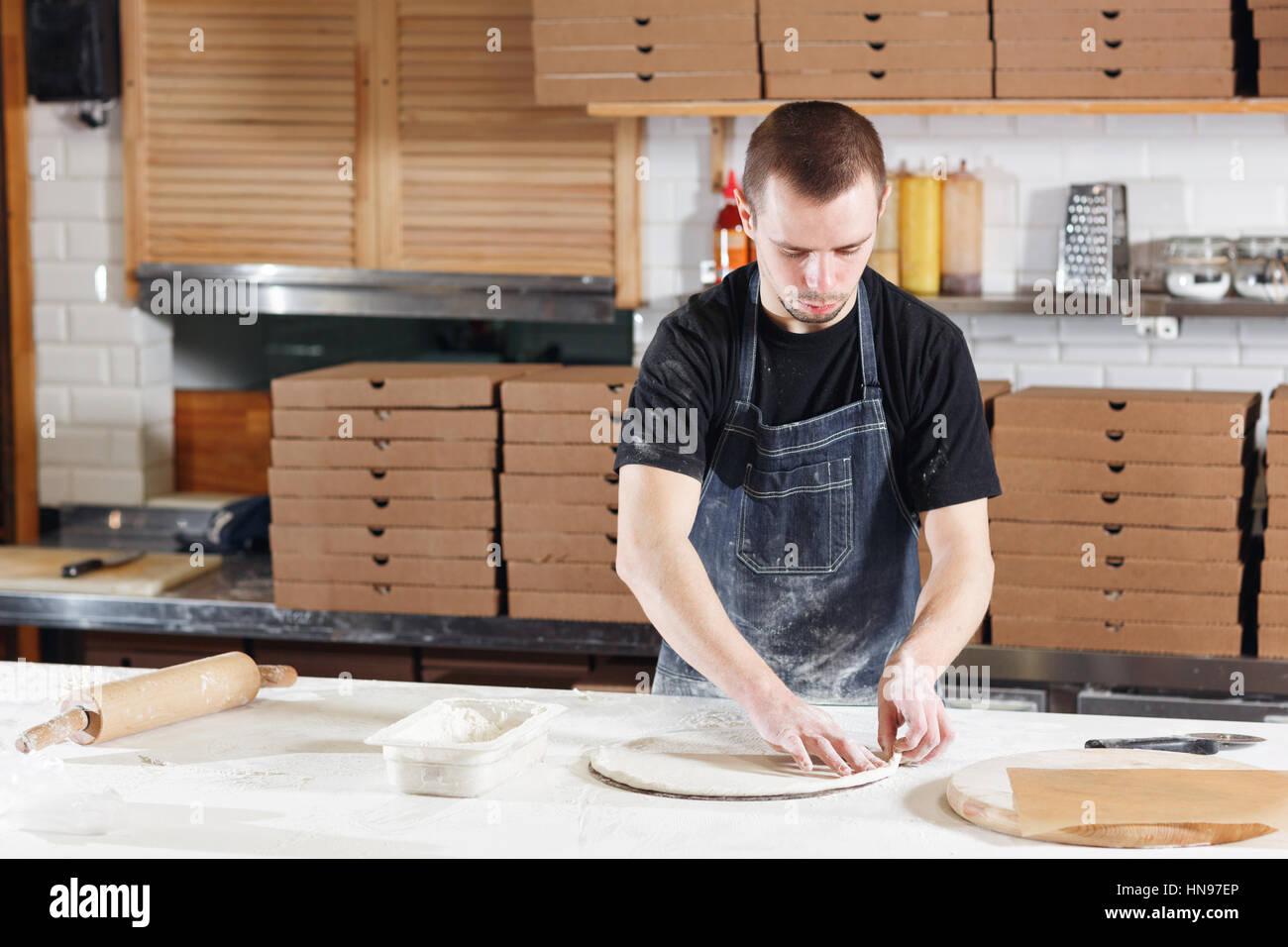 Roll out the dough. Closeup hand of chef baker in uniform blue apron ...