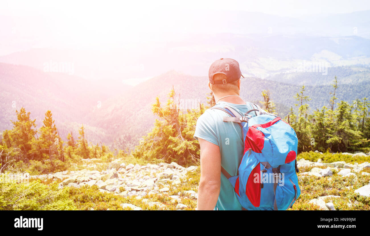 Young man with backpack hiking in the mountains. Summer backpacking ...