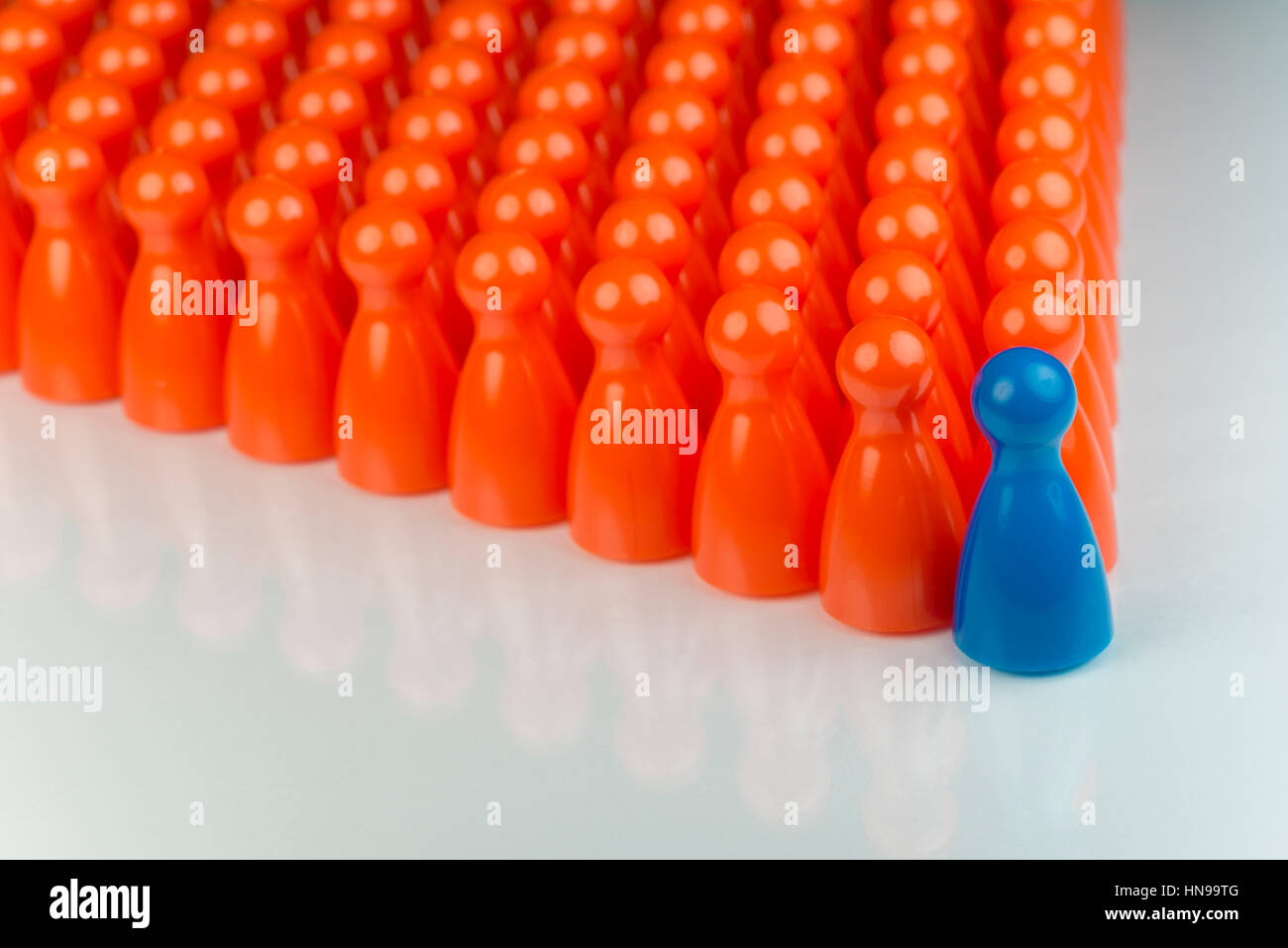 Conceptual orange game pawns and a blue play pawn as abstract display ...