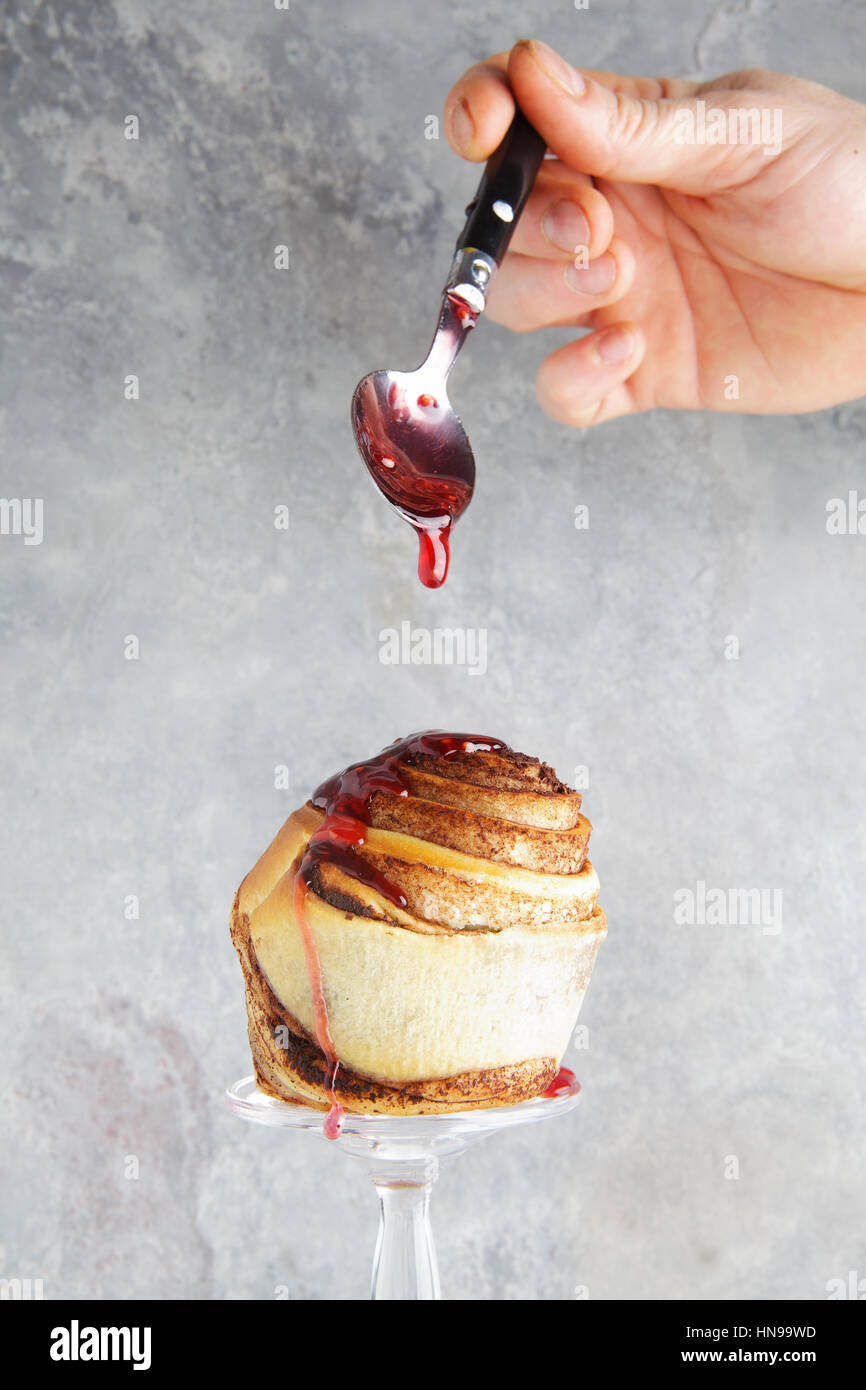 pouring the jam on cinnamon bun Stock Photo - Alamy