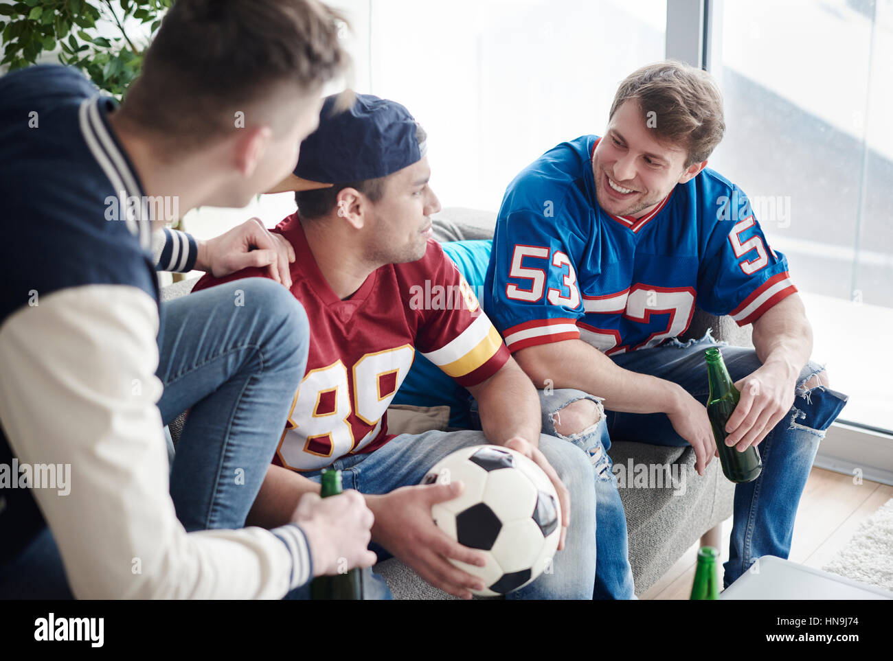 Friends seated on a sofa and watching soccer game Stock Photo - Alamy