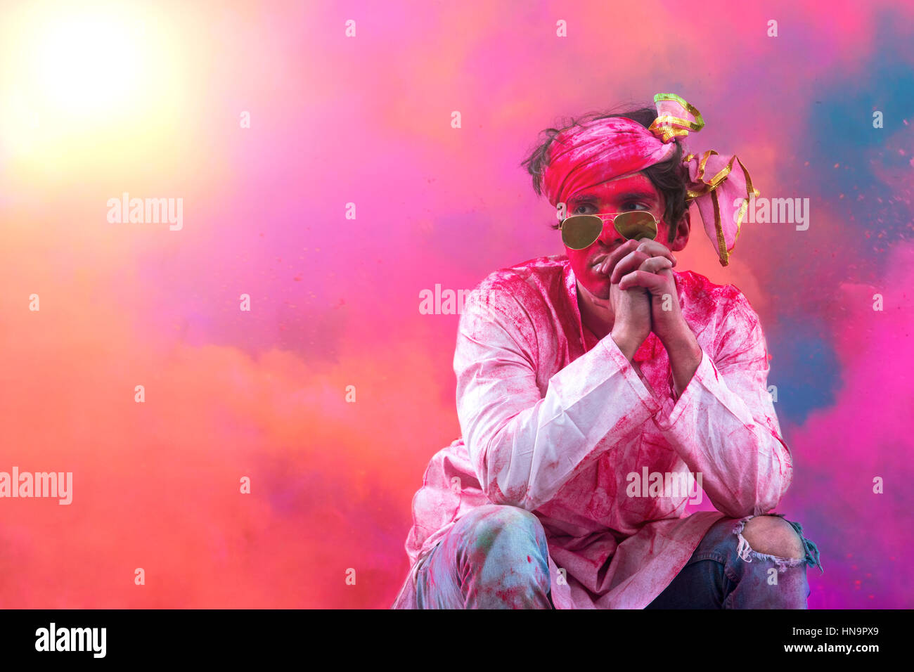 Young Indian Man sitting on bench, covered in colored powder during ...