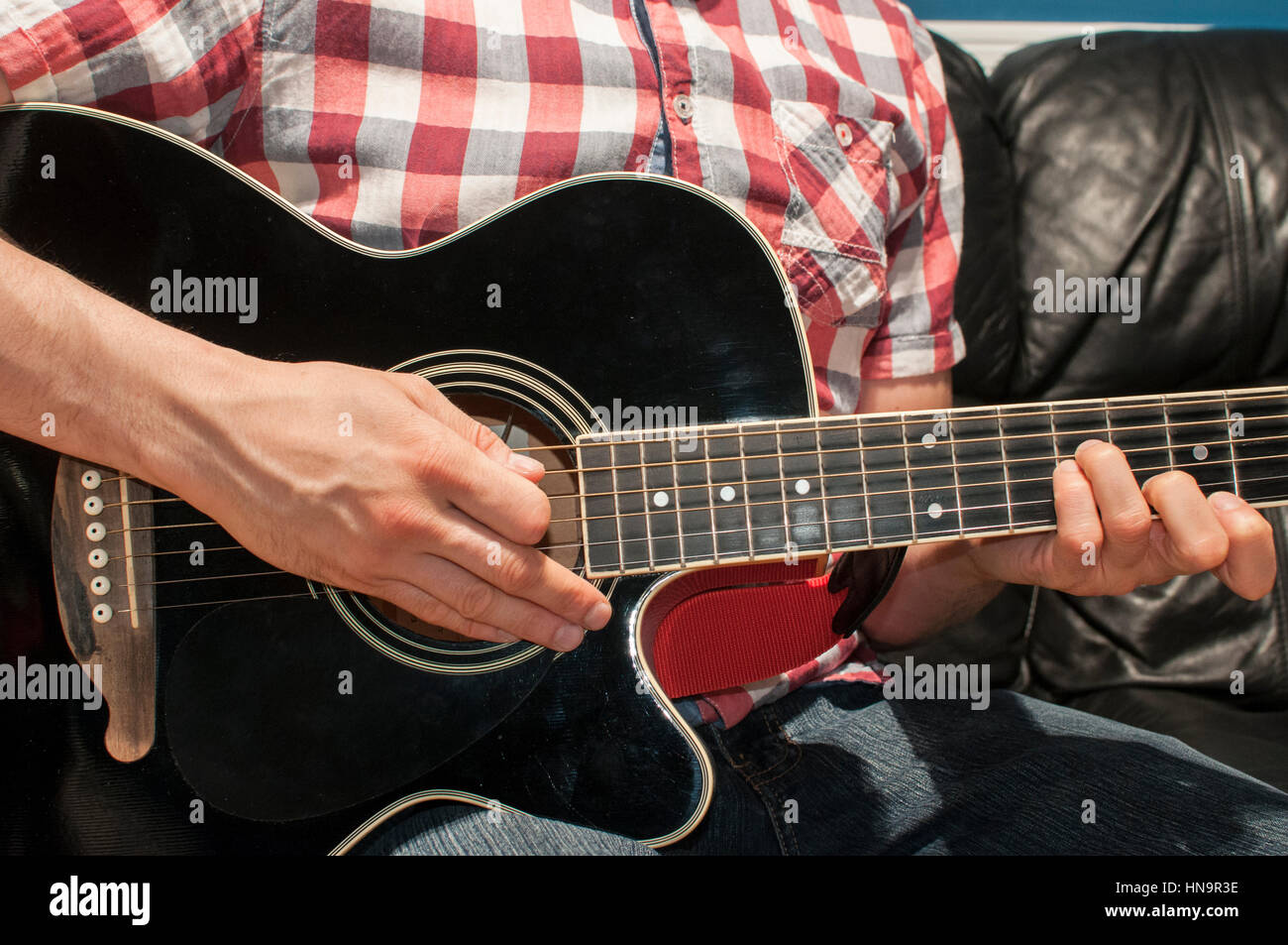 Man playing music on an acoustic guitar on a couch Stock Photo - Alamy