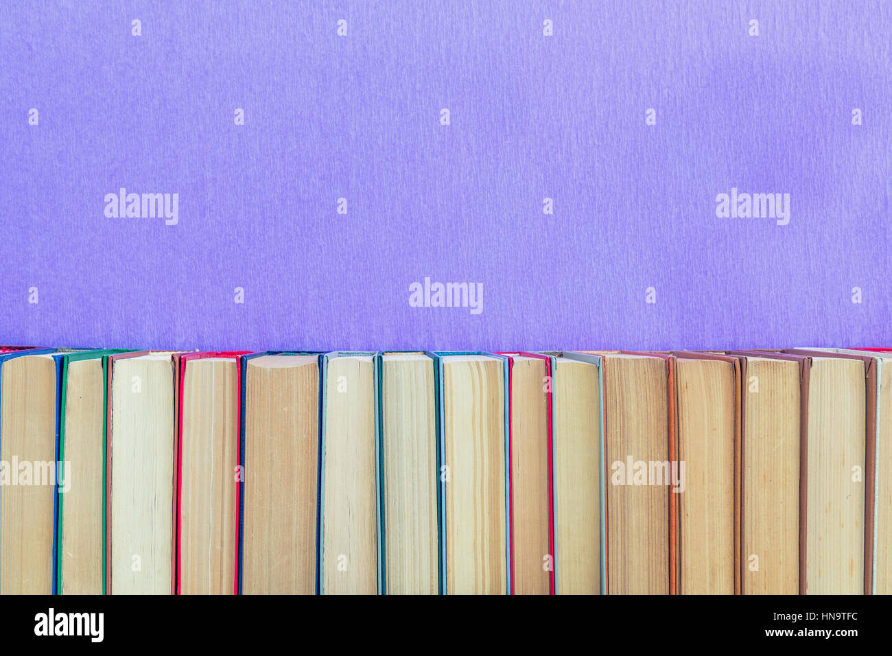 Books background. Many different books on violet wall Stock Photo - Alamy