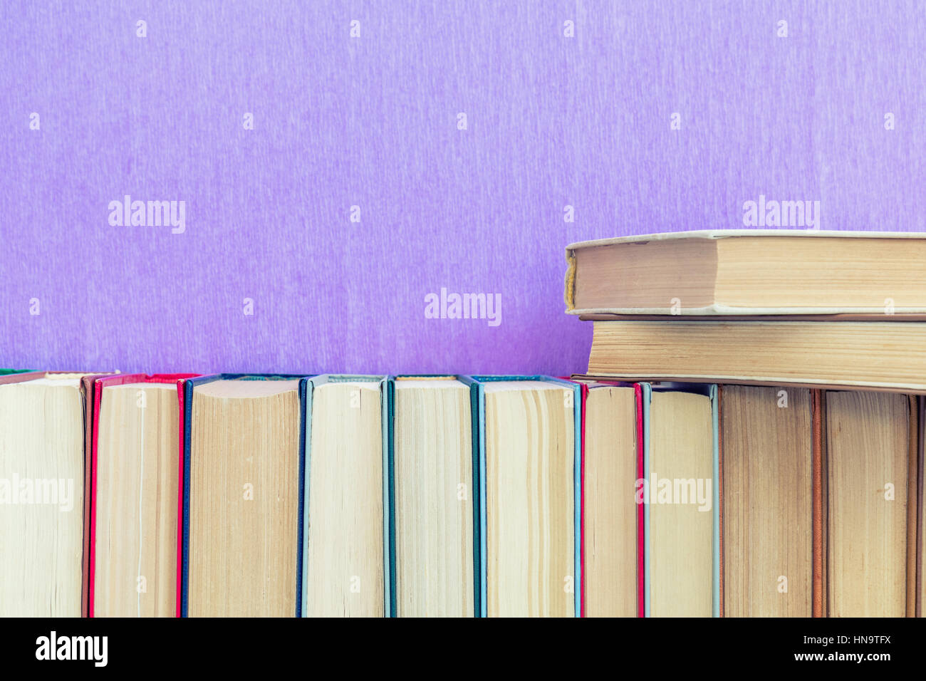 Books background. Many different books on violet wall Stock Photo - Alamy