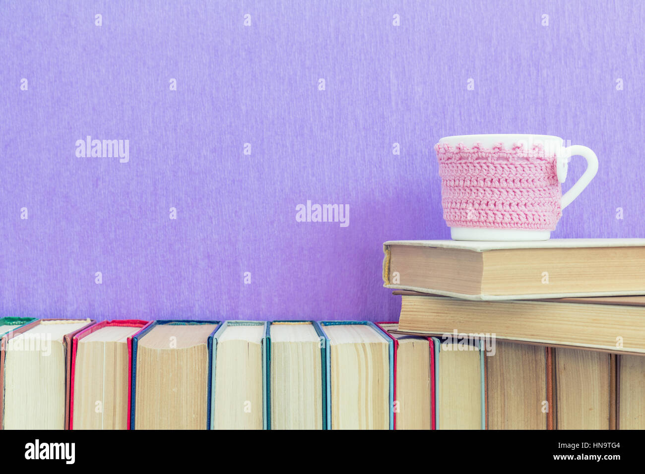 Books background. Many different books on violet wall. Cup of tea on ...