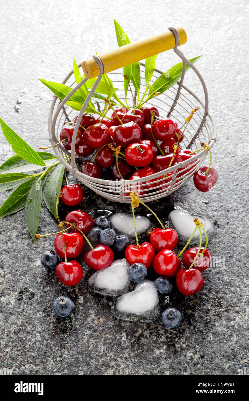 basket with fresh juicy Berries and ice cubes in the shape of heart ...