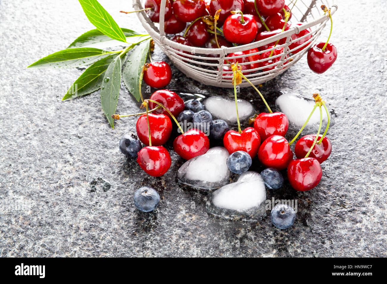 basket with fresh juicy Berries and ice cubes in the shape of heart ...
