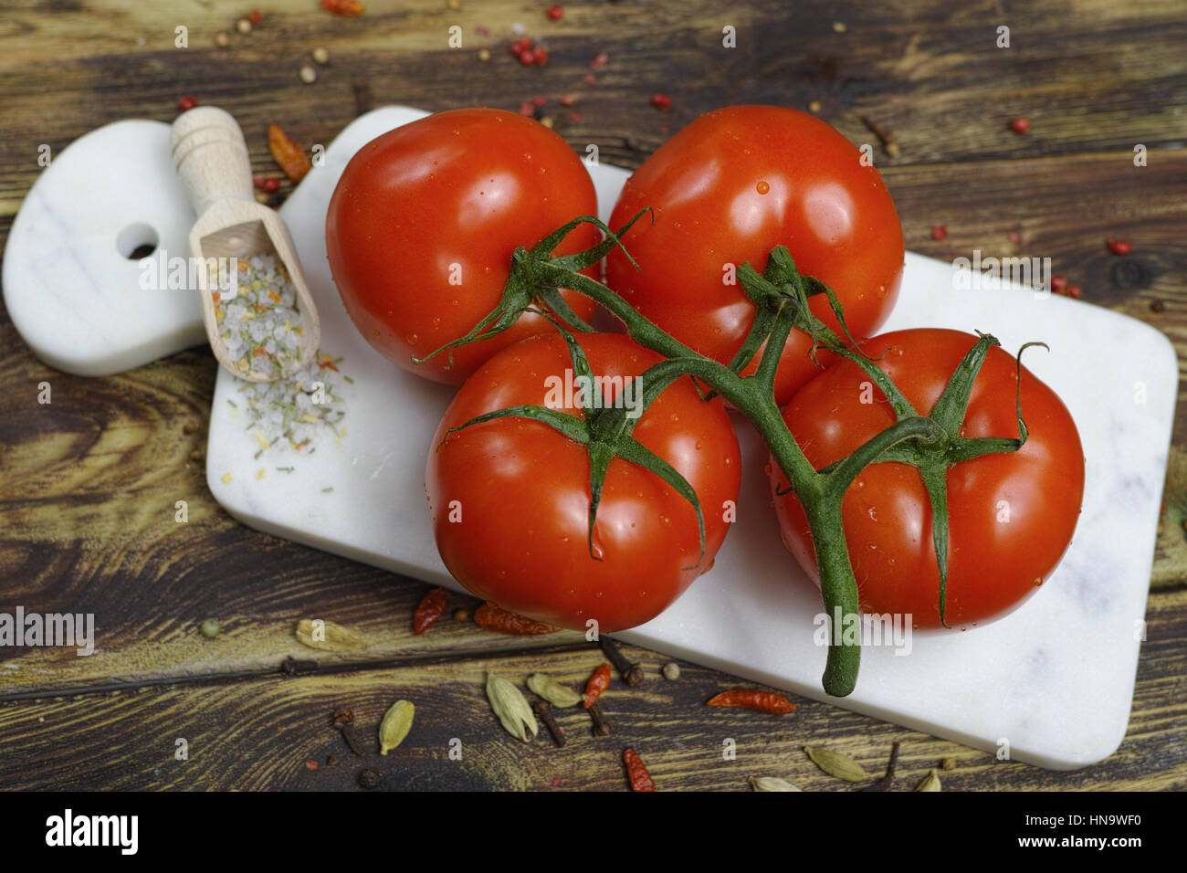 Raw Organic Red Tomatoes on the Vine on white marble plank Stock Photo ...