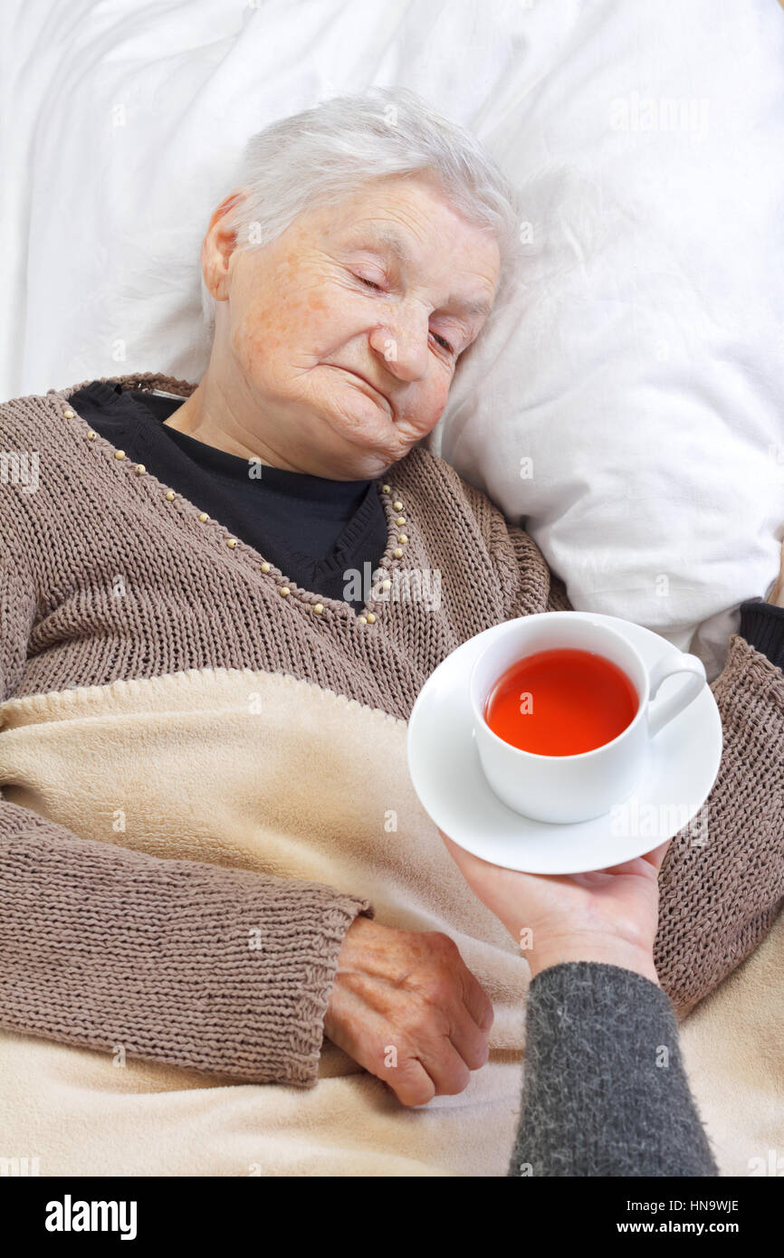 Picture of a woman hand giving tea to an elderly woman Stock Photo - Alamy