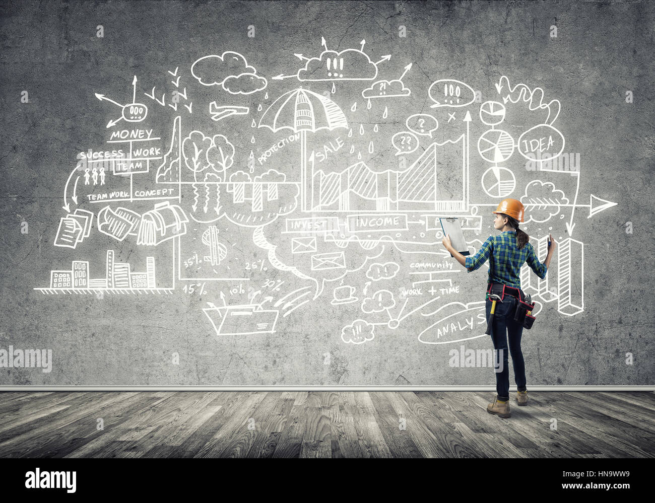 Back view of engineer woman in hardhat and sketched concept on wall ...