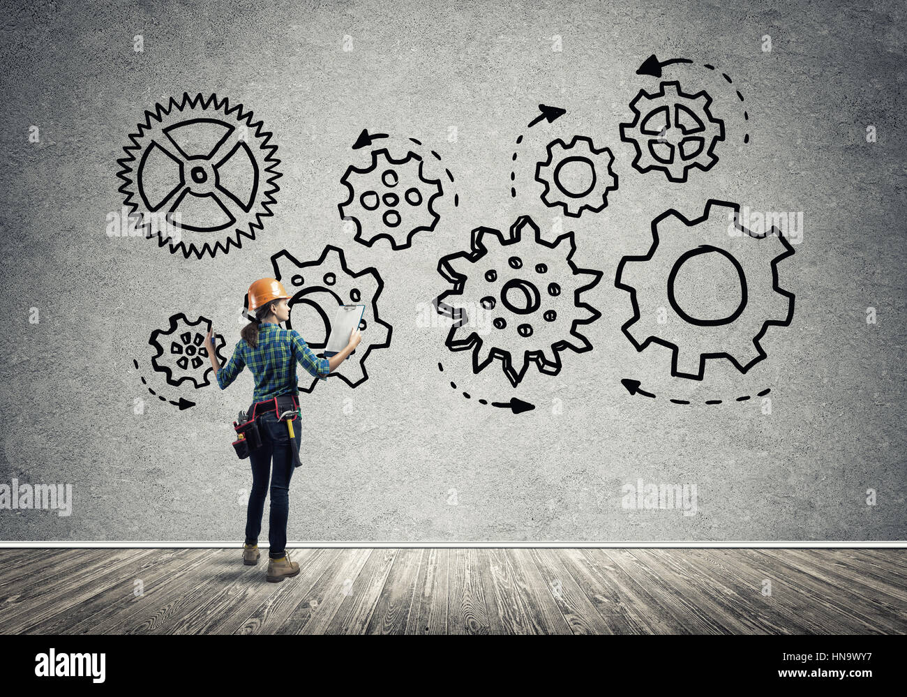 Back view of engineer woman in hardhat and sketched concept of teamwork ...
