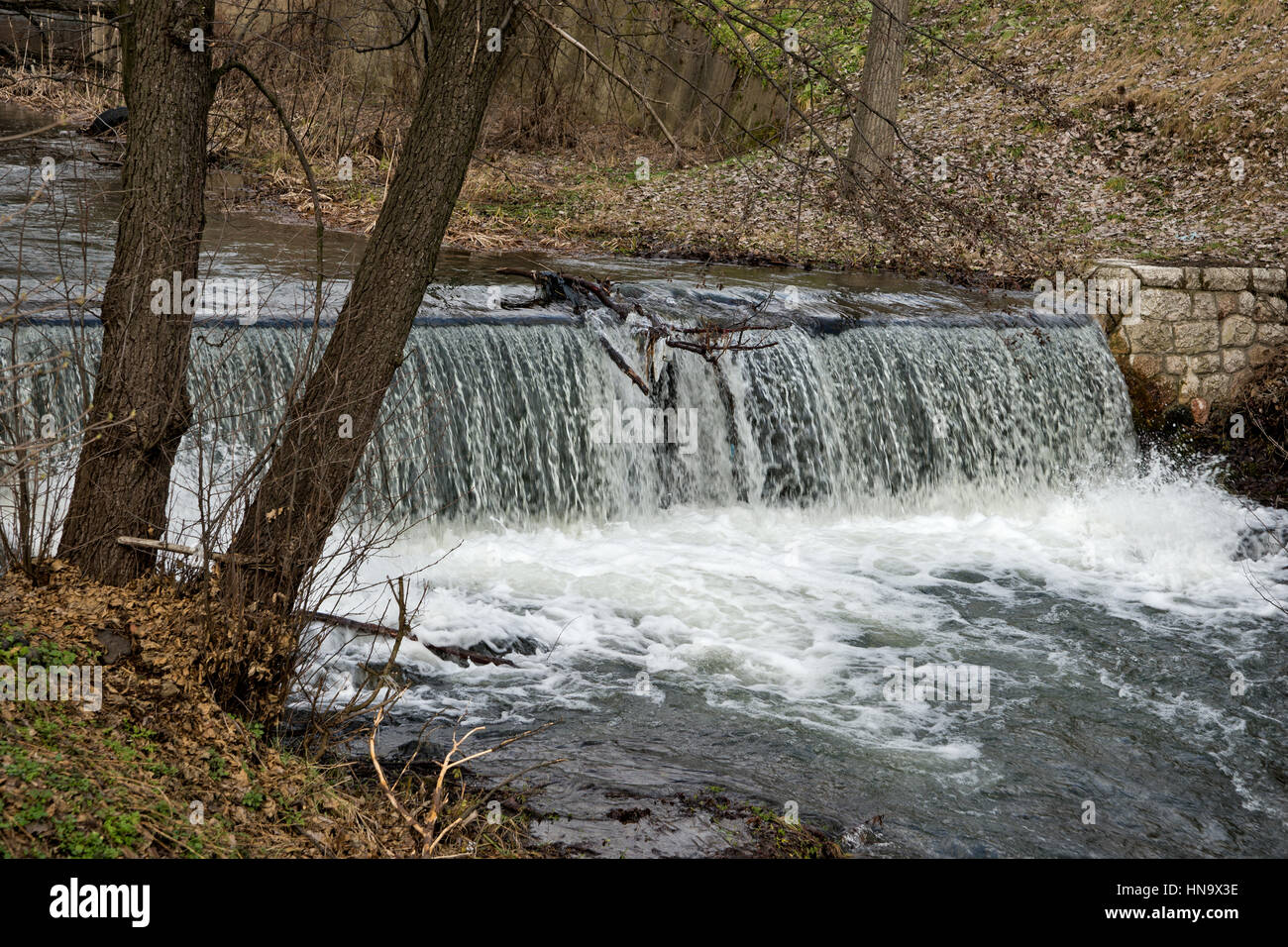 A small waterfall on the river with trees, branches and leaves Stock ...