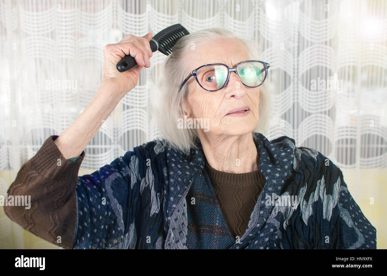Senior woman combs her hair at home Stock Photo - Alamy