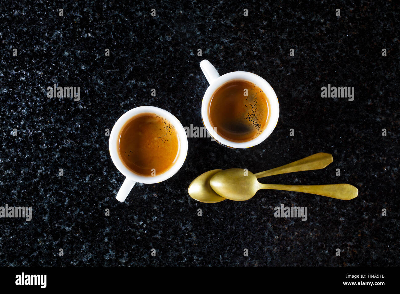 two cups of fresh Coffee Espresso on black Marble and two golden ...