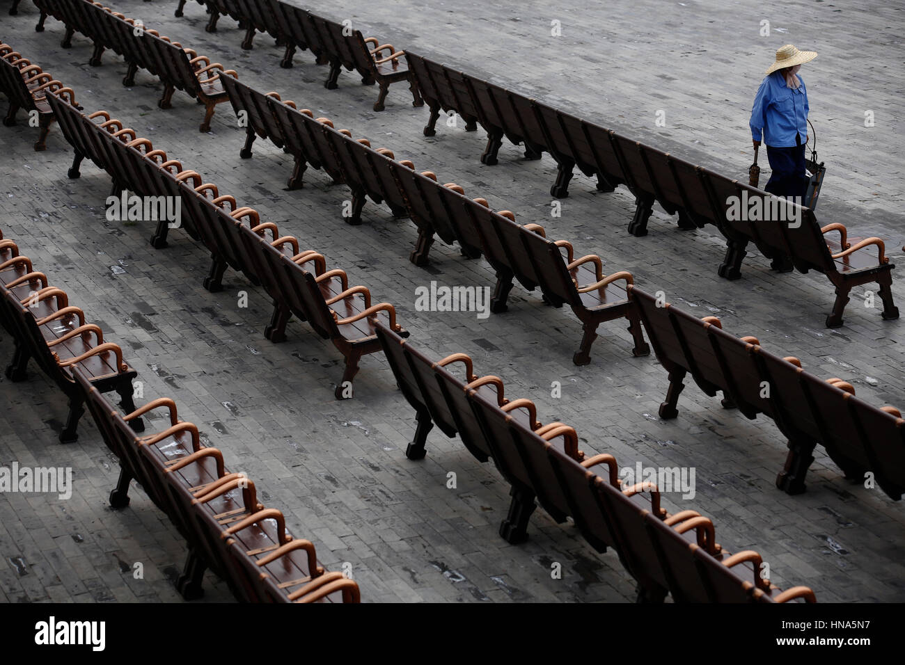 A cleaner passes benches in the Forbidden City in Beijing, China ...