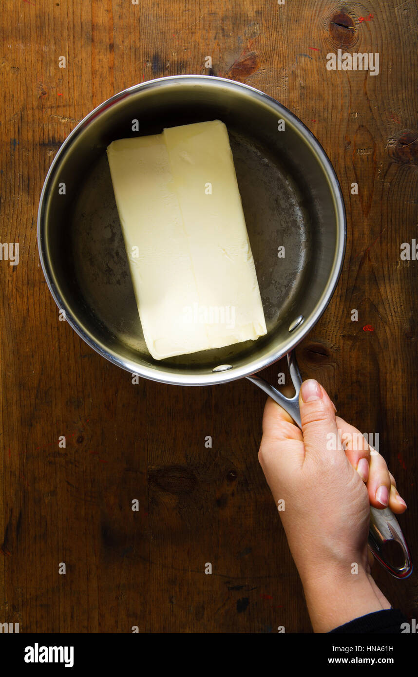 piece of butter in a pan . female hand Stock Photo - Alamy