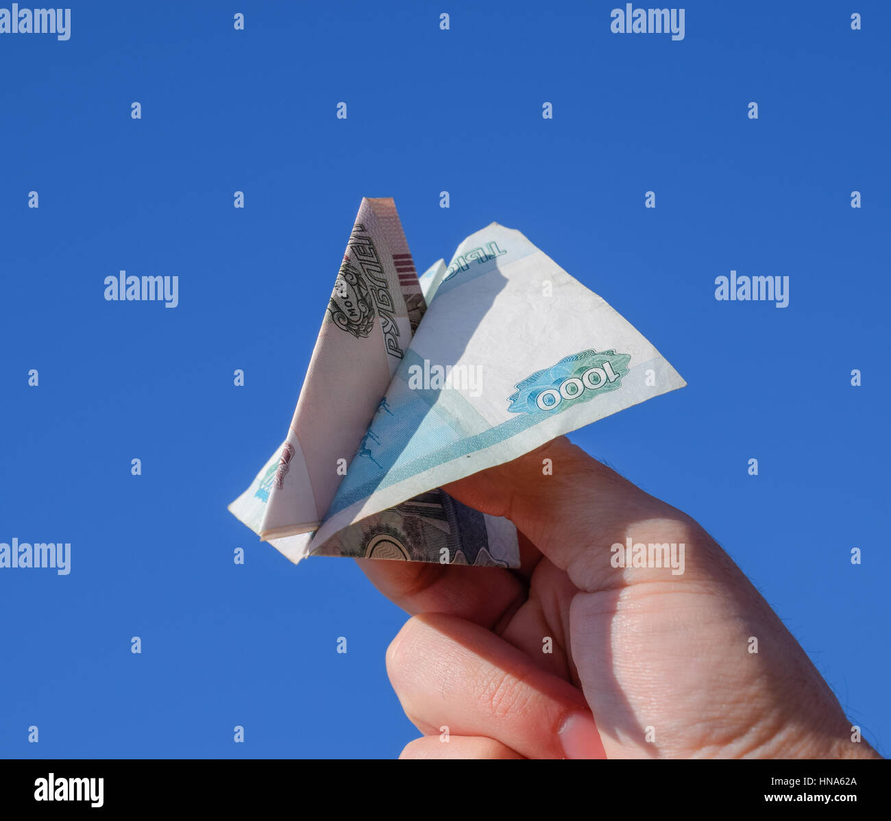 Denominations of Russian money, folded in the airplane against the blue ...