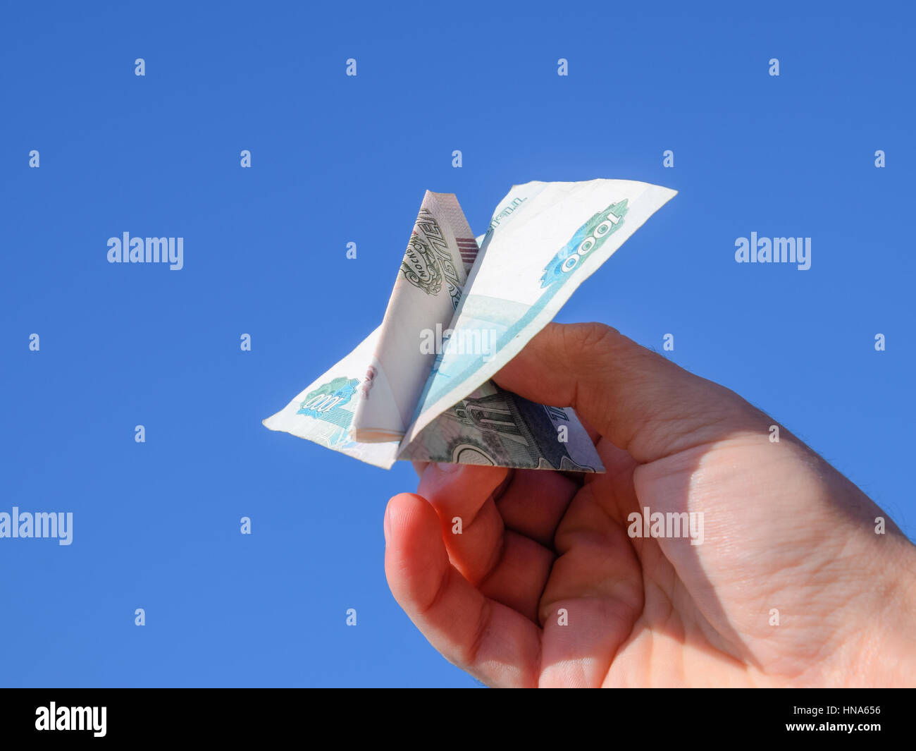 Denominations of Russian money, folded in the airplane against the blue ...